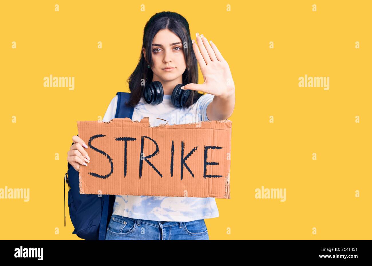 Young beautiful girl wearing student backpack holding strike banner ...