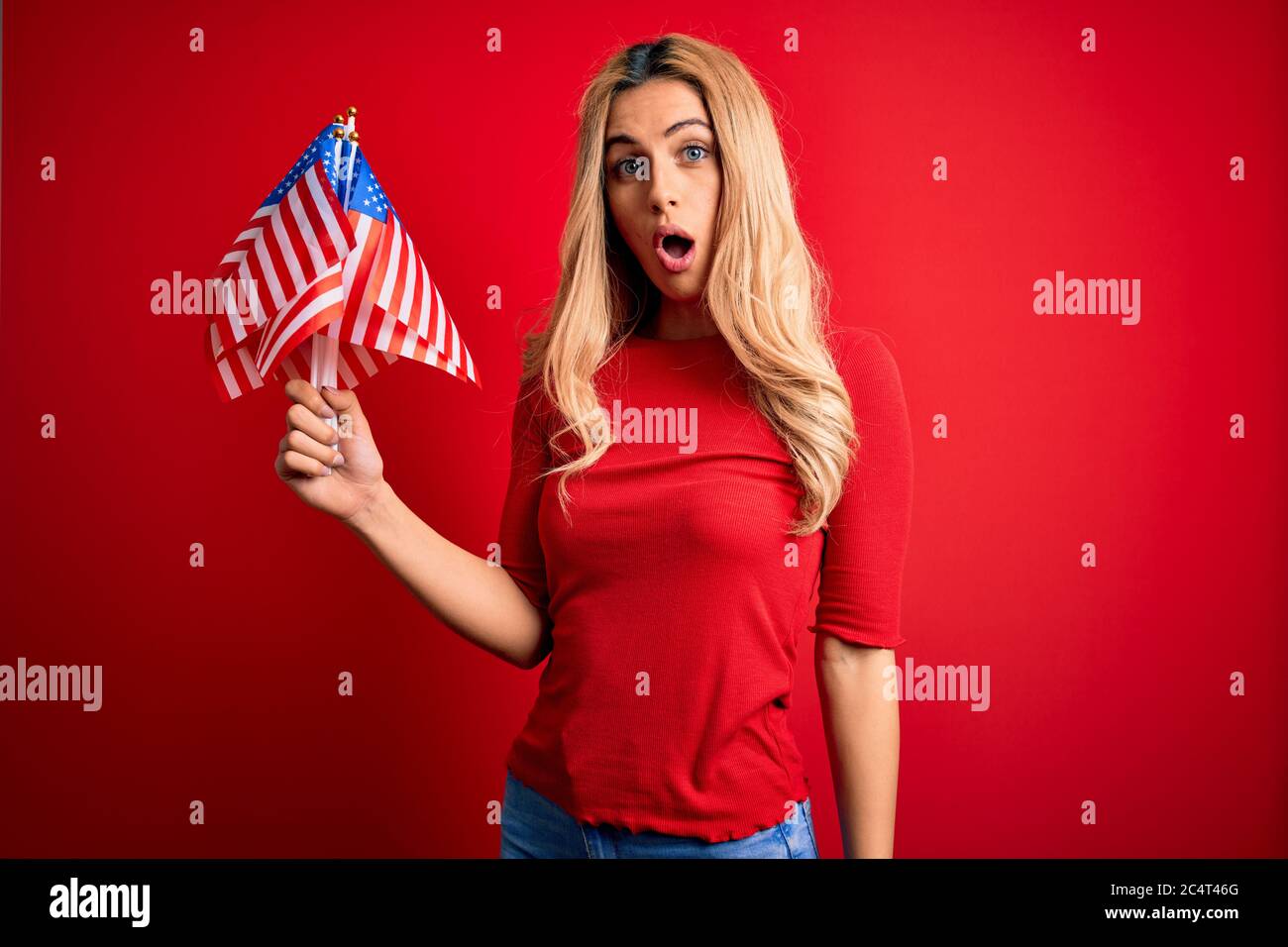 Beautiful blonde patriotic woman holding united states flags ...