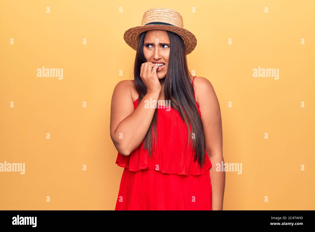 Young beautiful brunette woman wearing summer hat and dress looking ...