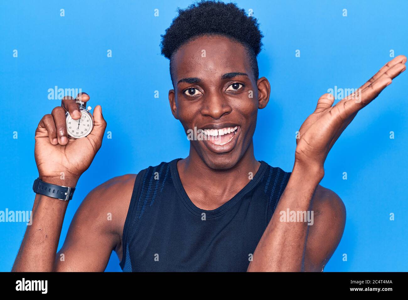 Young african american man holding stopwatch celebrating victory with ...
