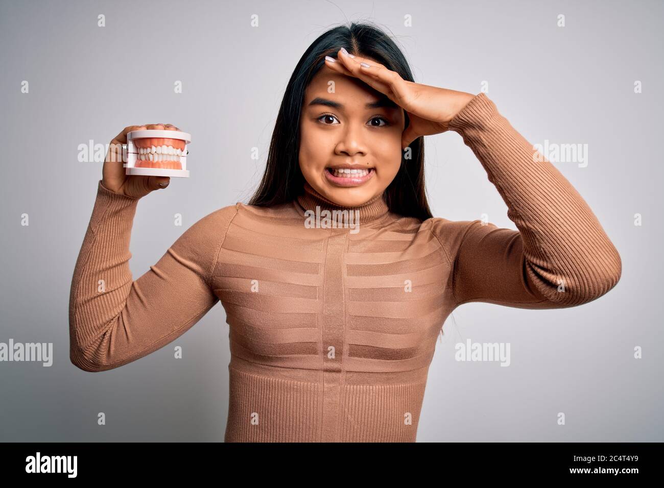 Young asian girl asking for dental care holding plastic denture teeth ...
