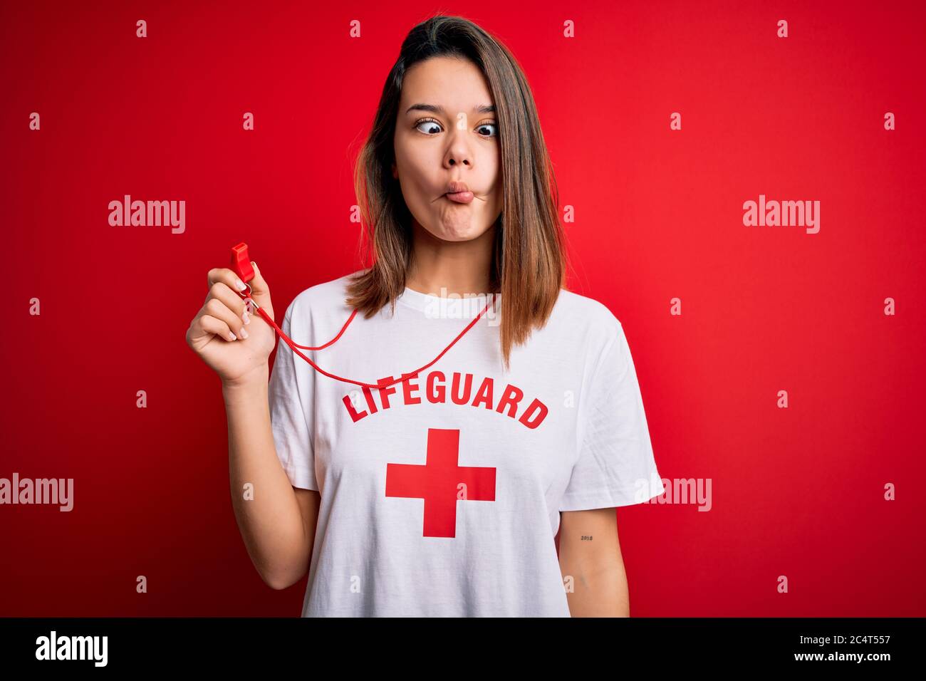 Young beautiful brunette lifeguard girl wearing t-shirt with red cross ...
