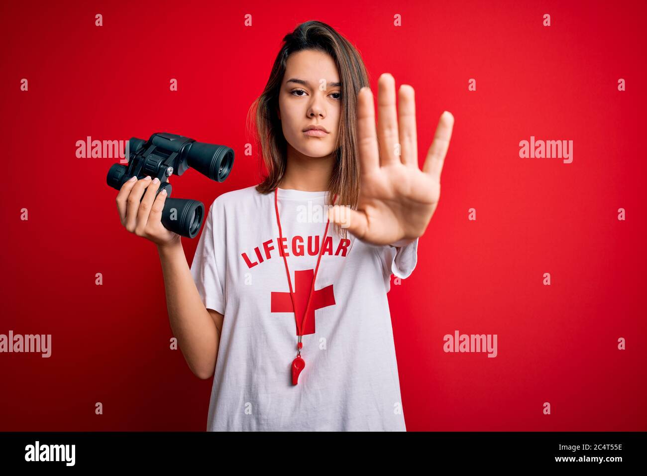 Young beautiful lifeguard girl wearing whistle using binoculars over ...
