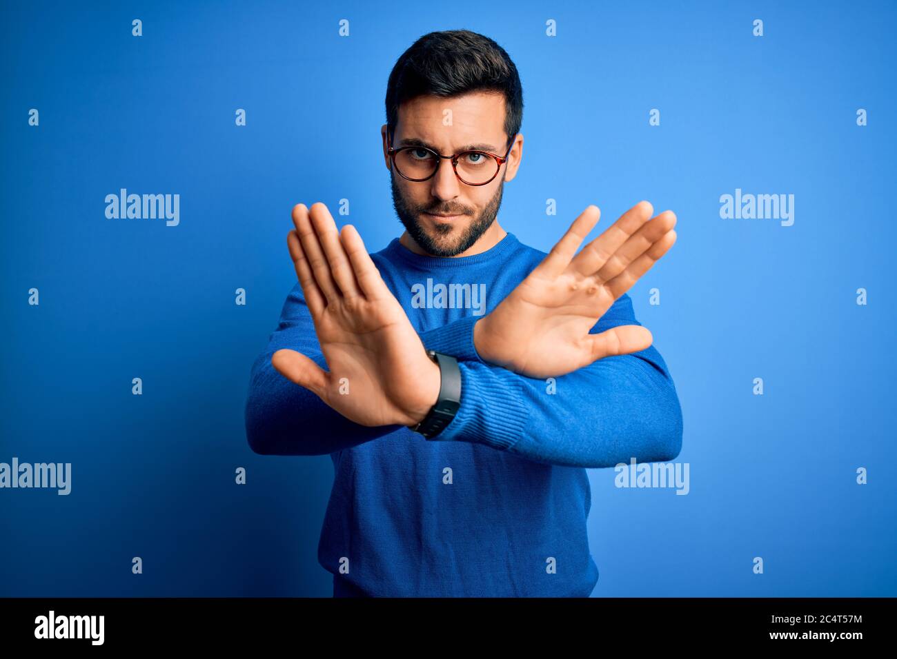 Young handsome man with beard wearing casual sweater and glasses over ...