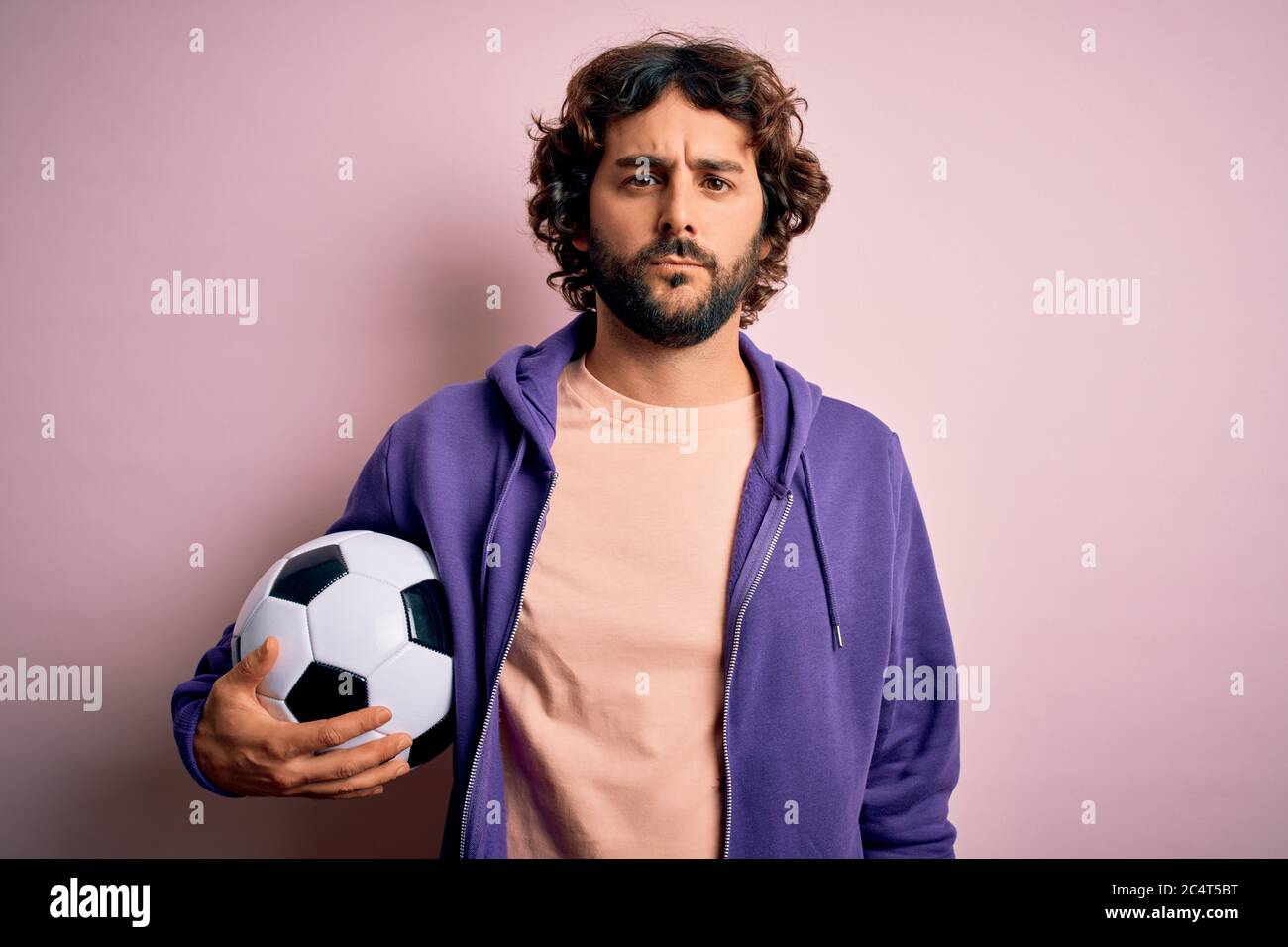 Handsome player man with beard playing soccer holding football ball ...