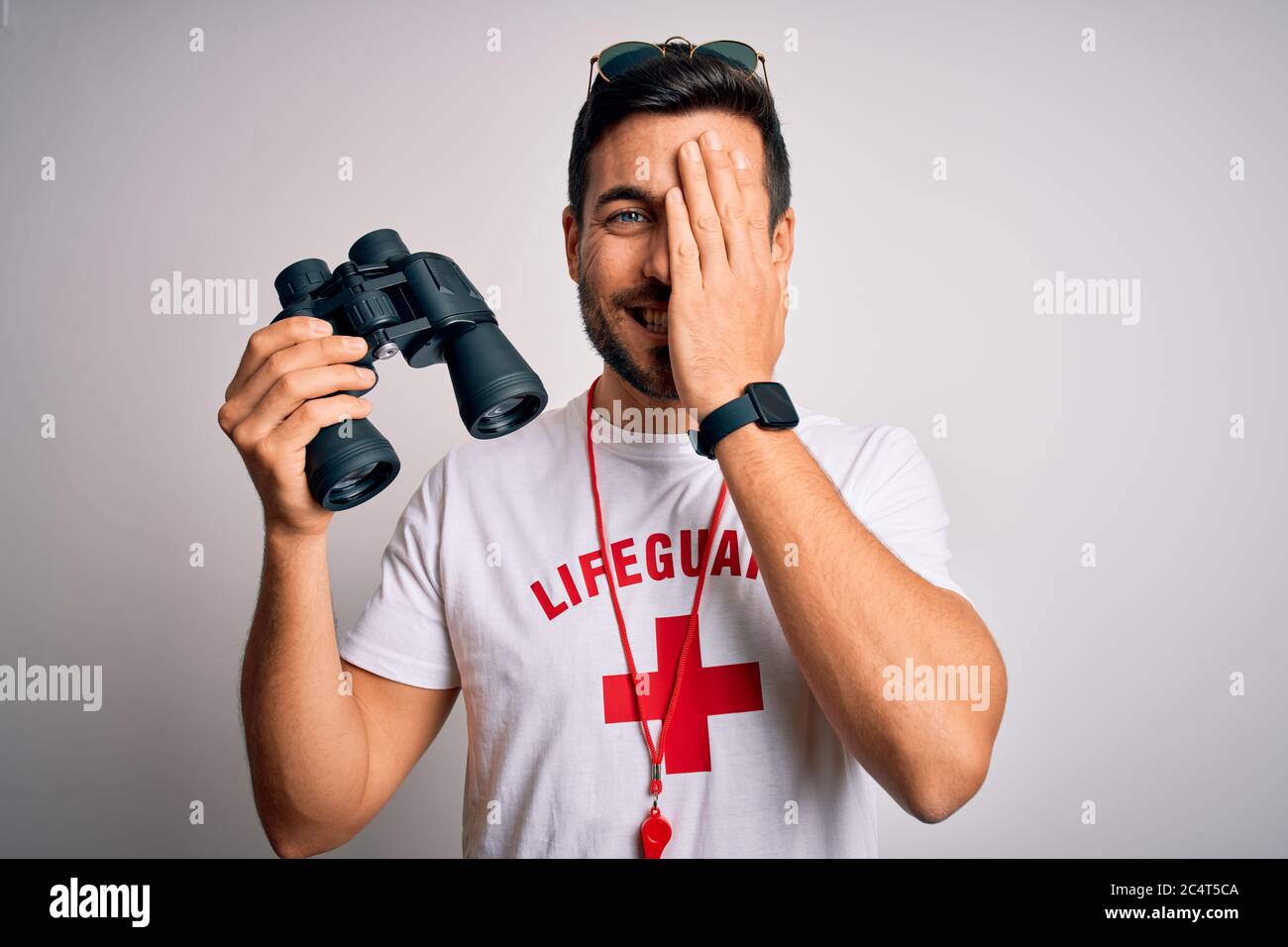 Young lifeguard man with beard wearing t-shirt with red cross and ...