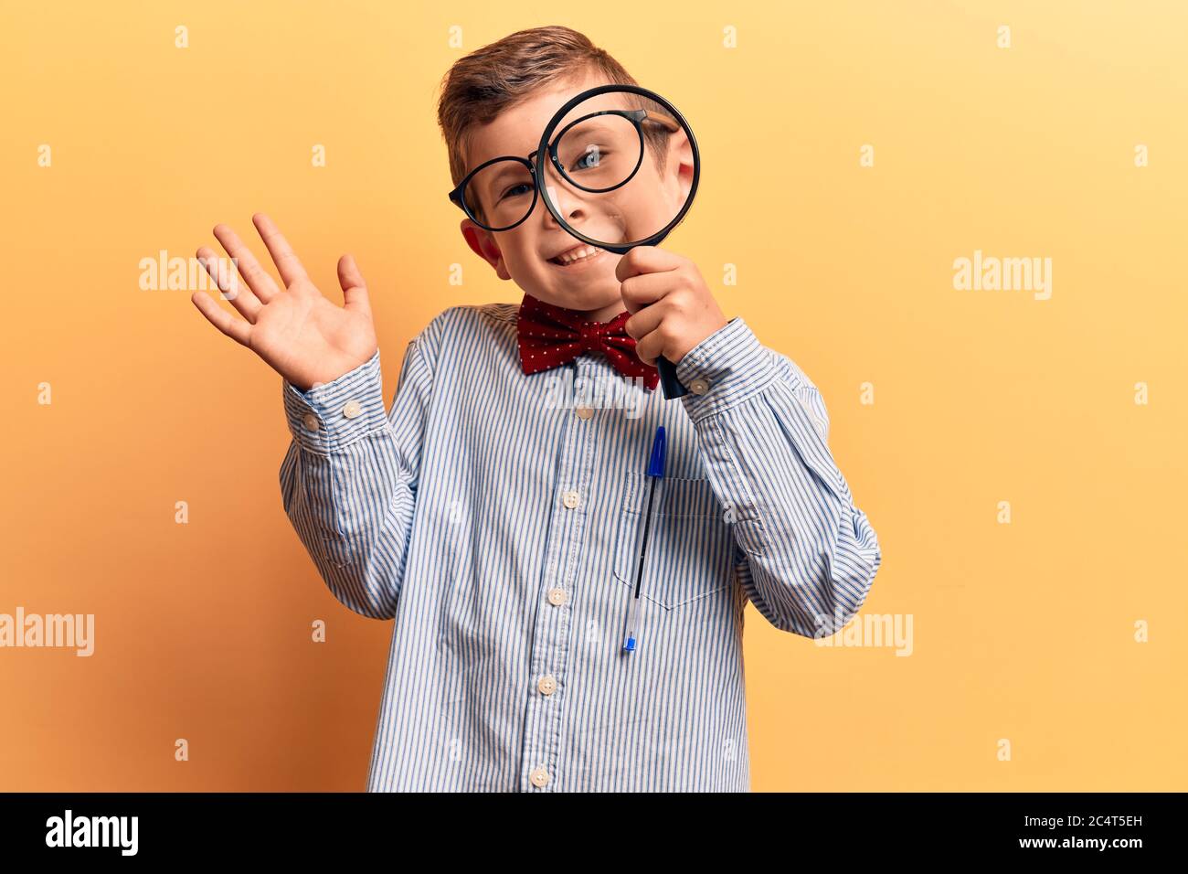 Cute blond kid wearing nerd bow tie and glasses holding magnifying ...