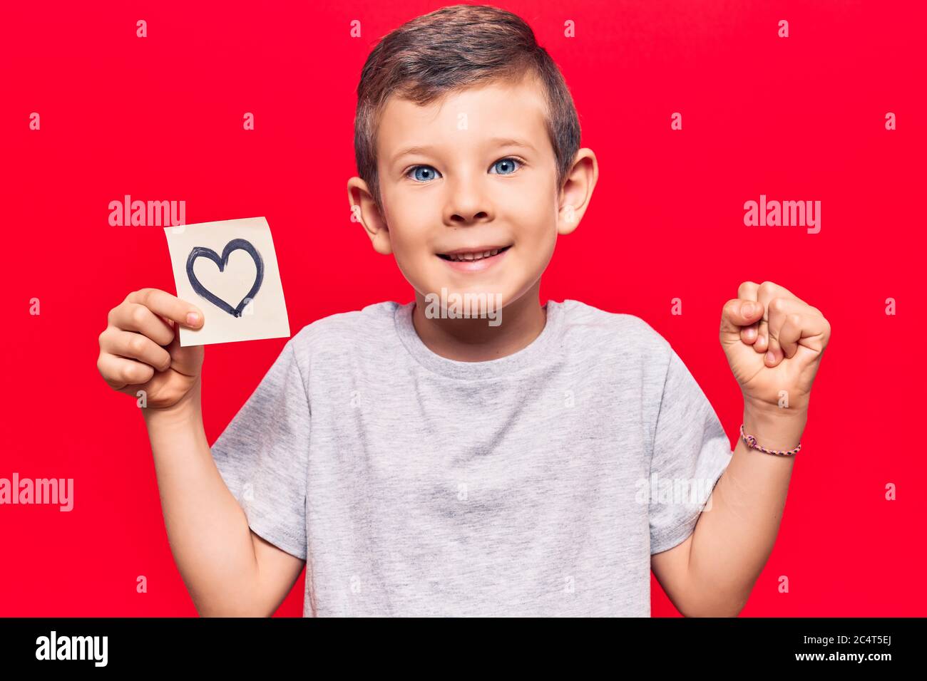 Cute blond kid holding heart reminder screaming proud, celebrating ...