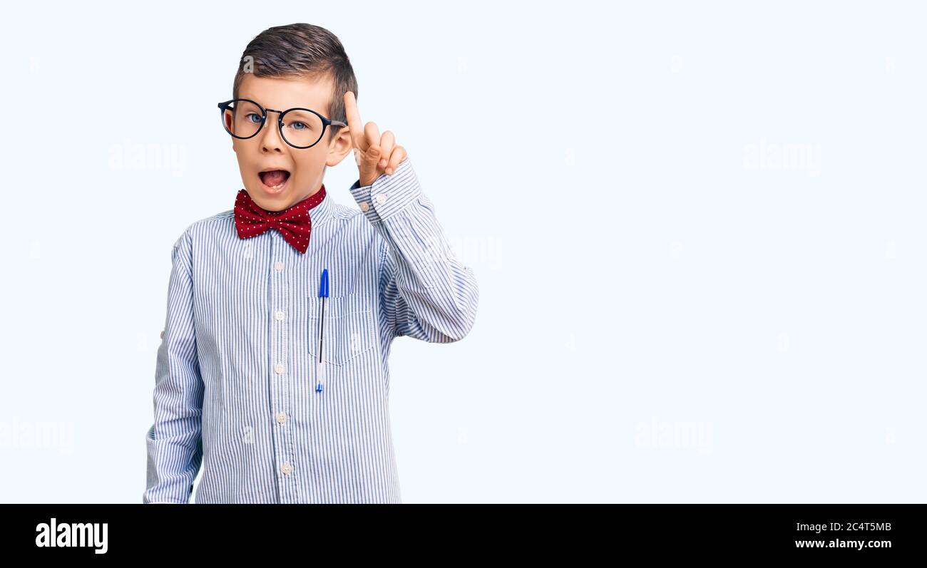 Cute blond kid wearing nerd bow tie and glasses pointing finger up with ...