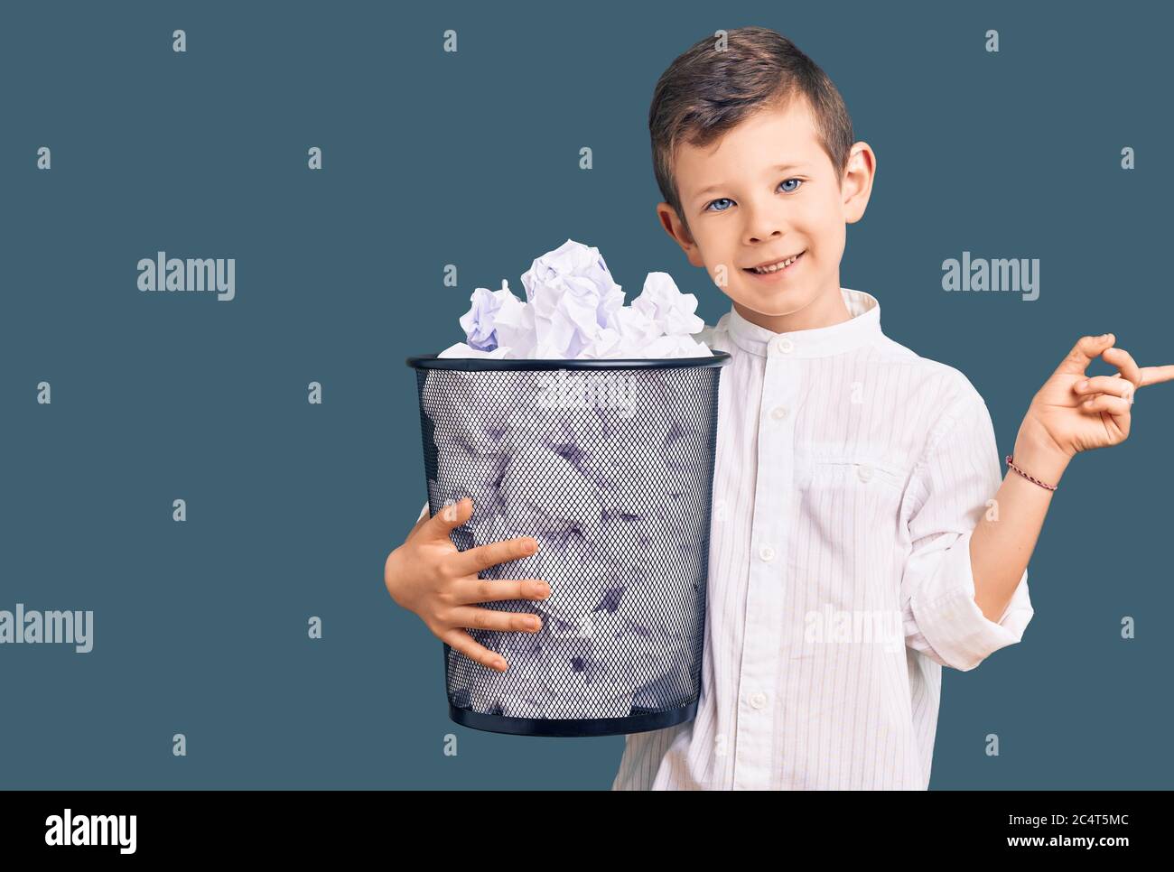 Cute blond kid holding paper bin full of crumpled papers smiling happy ...