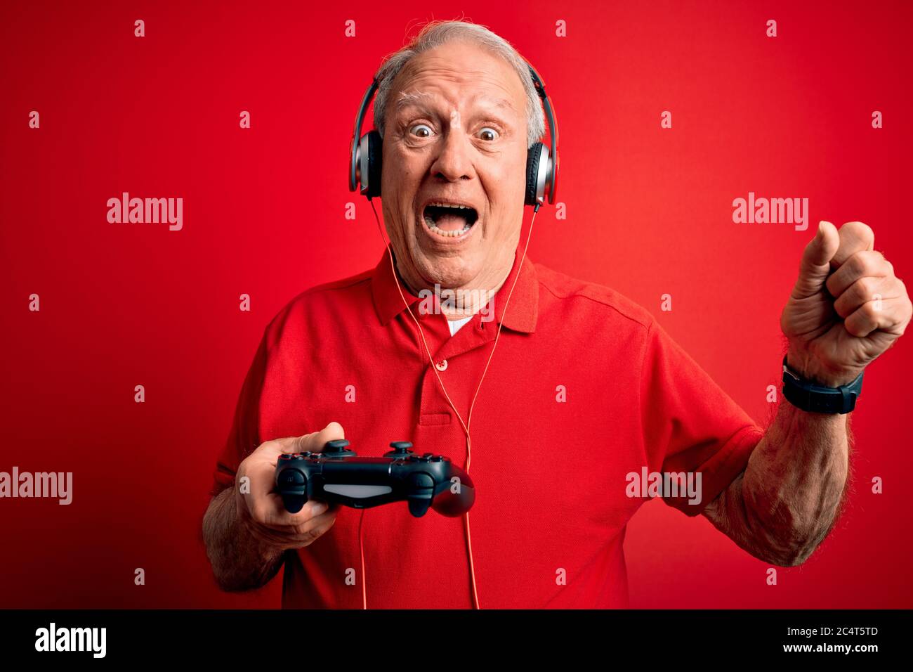 Senior grey haired gamer man playing video games using gamepad joystick ...
