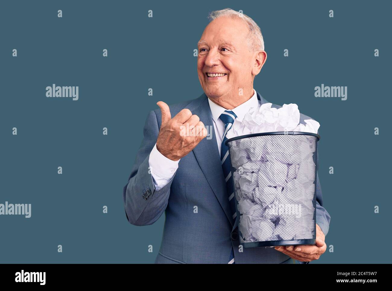 Senior handsome grey-haired man holding paper bin with crumpled ...