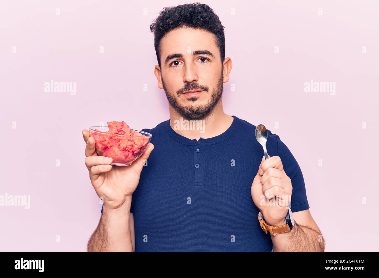Young hispanic man holding ice cream thinking attitude and sober ...