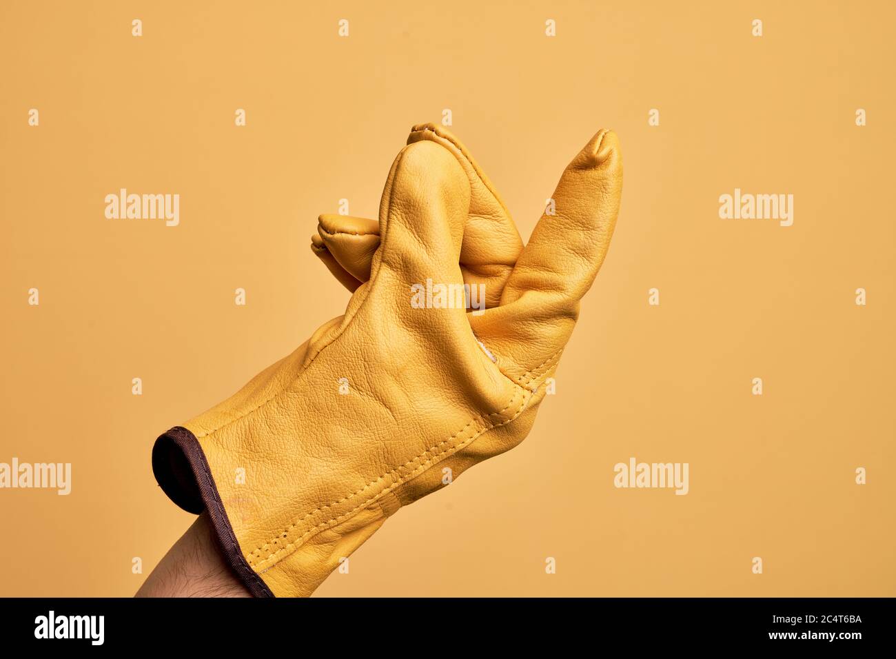 Hand of caucasian young man with gardener glove over isolated yellow ...