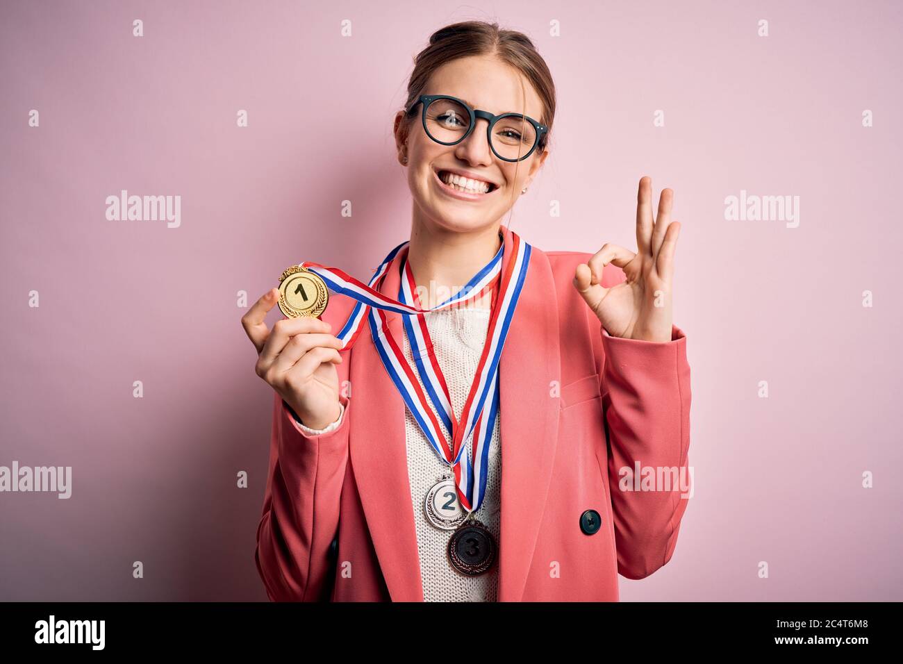 Young beautiful redhead woman wearing medals over isolated red ...