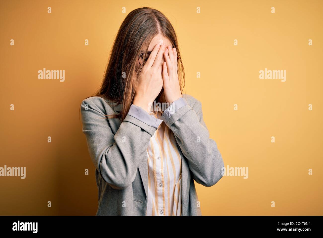 Young beautiful redhead woman wearing jacket and glasses over isolated ...