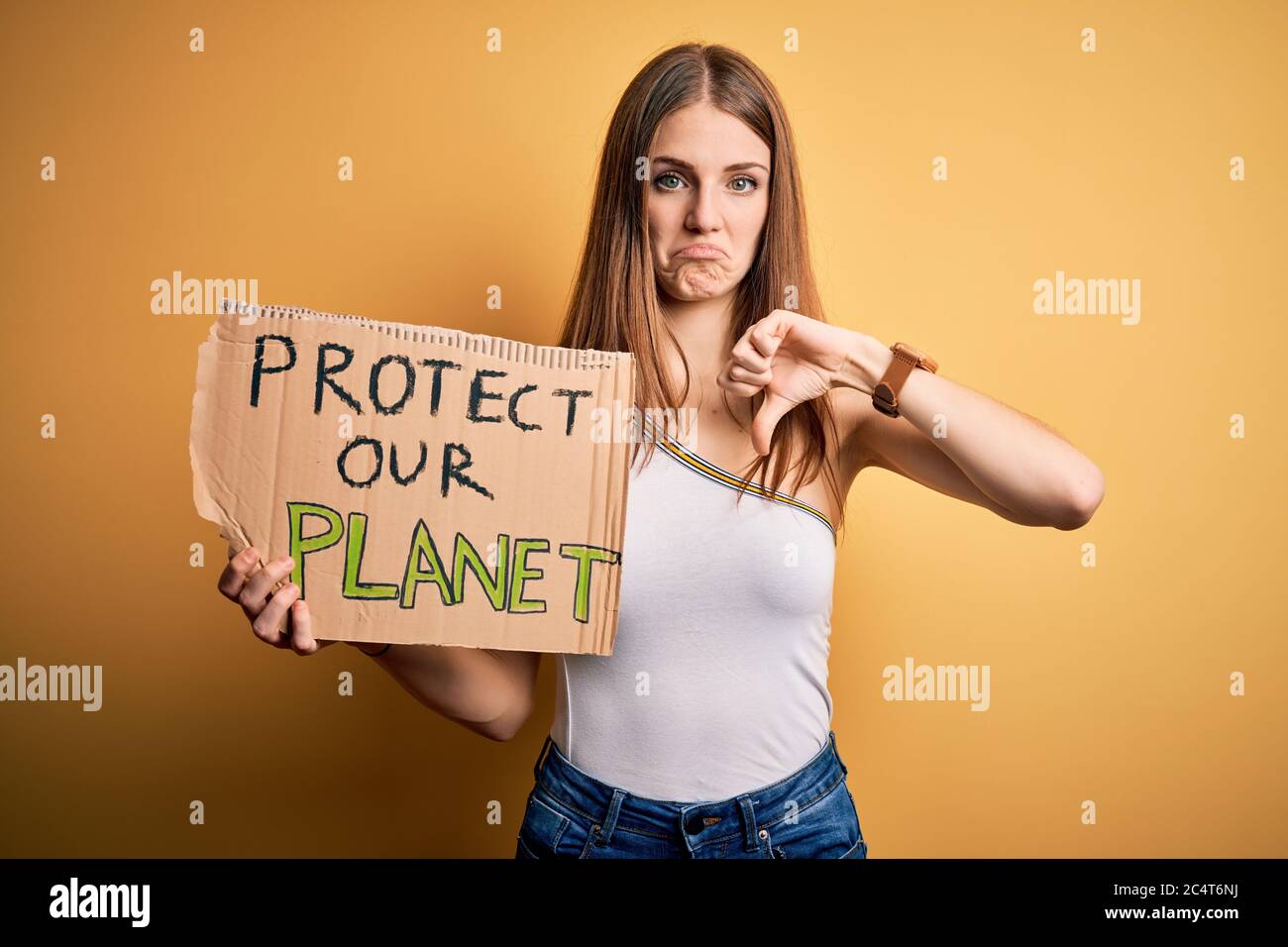 Young redhead woman asking for enviroment holding banner with protect ...