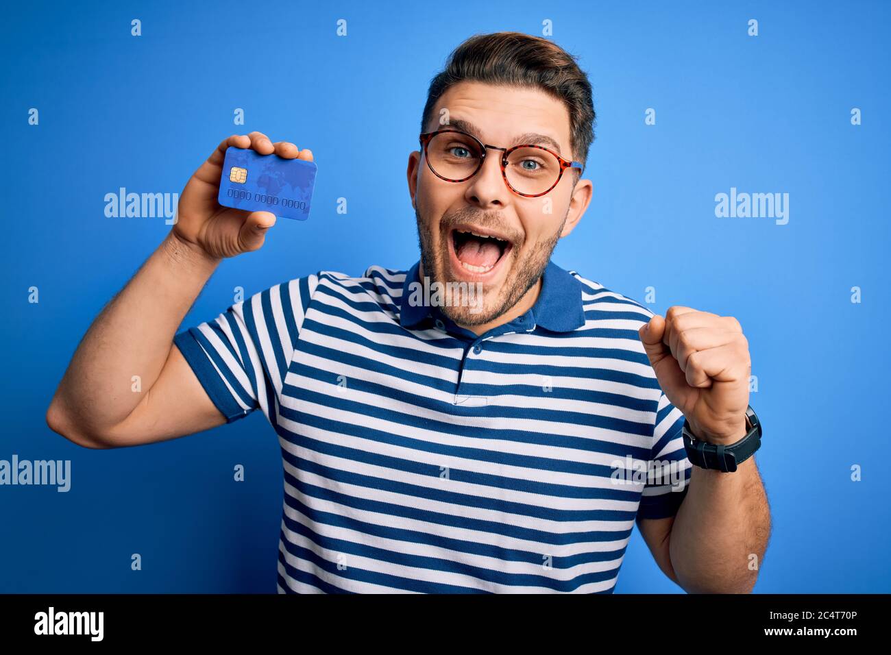 Young man with blue eyes wearing glasses and holding credit card over ...