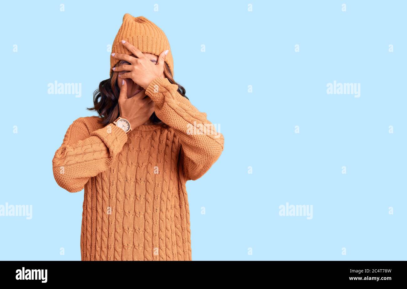 Young beautiful mixed race woman wearing wool sweater and winter hat ...