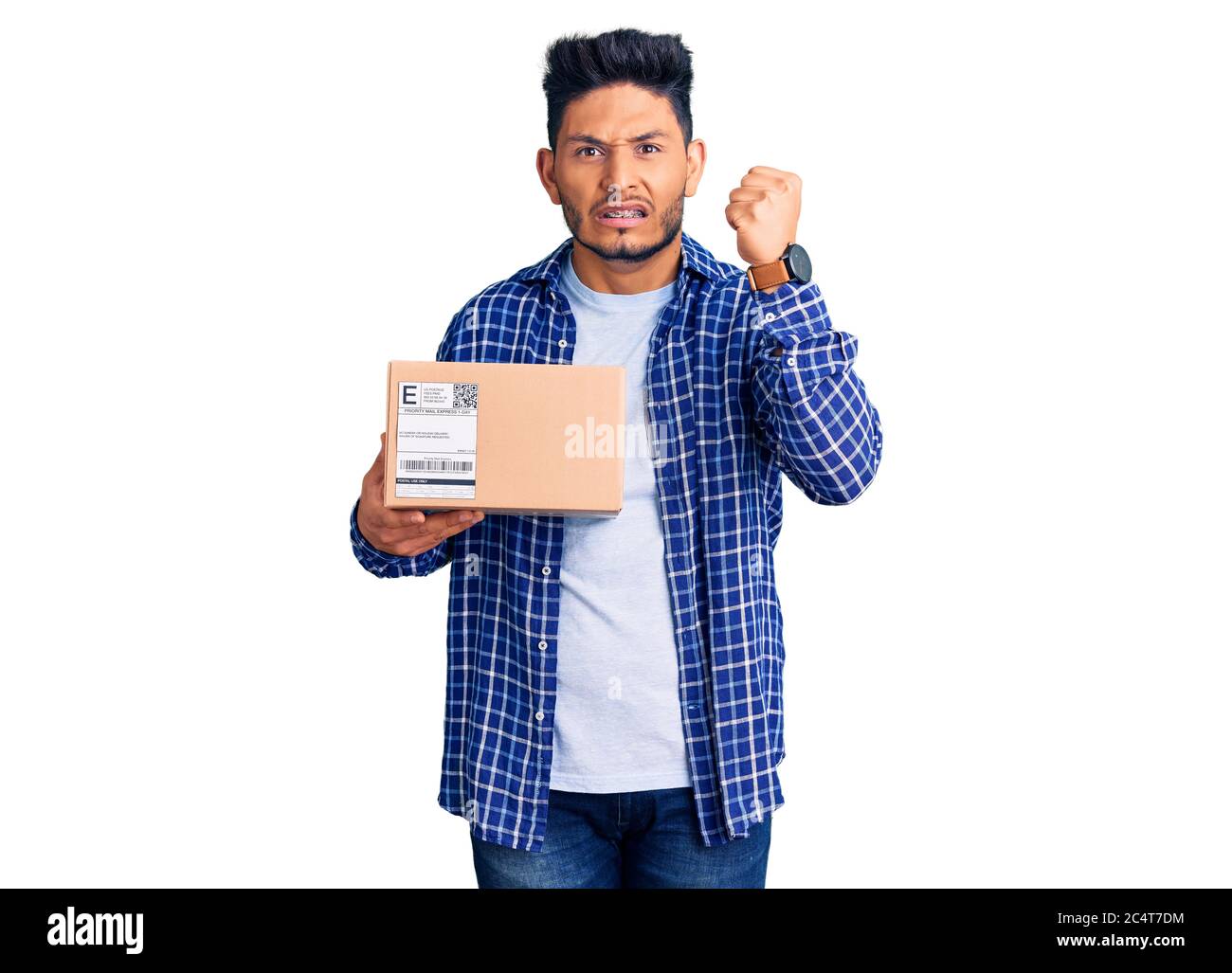 Handsome latin american young man holding delivery package annoyed and ...