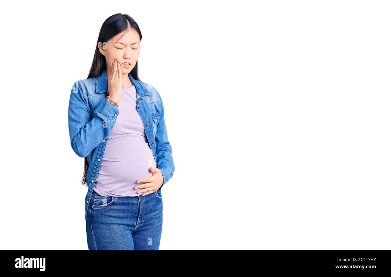 Young beautiful chinese woman pregnant expecting baby touching mouth ...