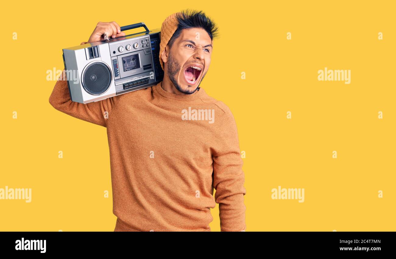 Handsome latin american young man holding boombox, listening to music ...