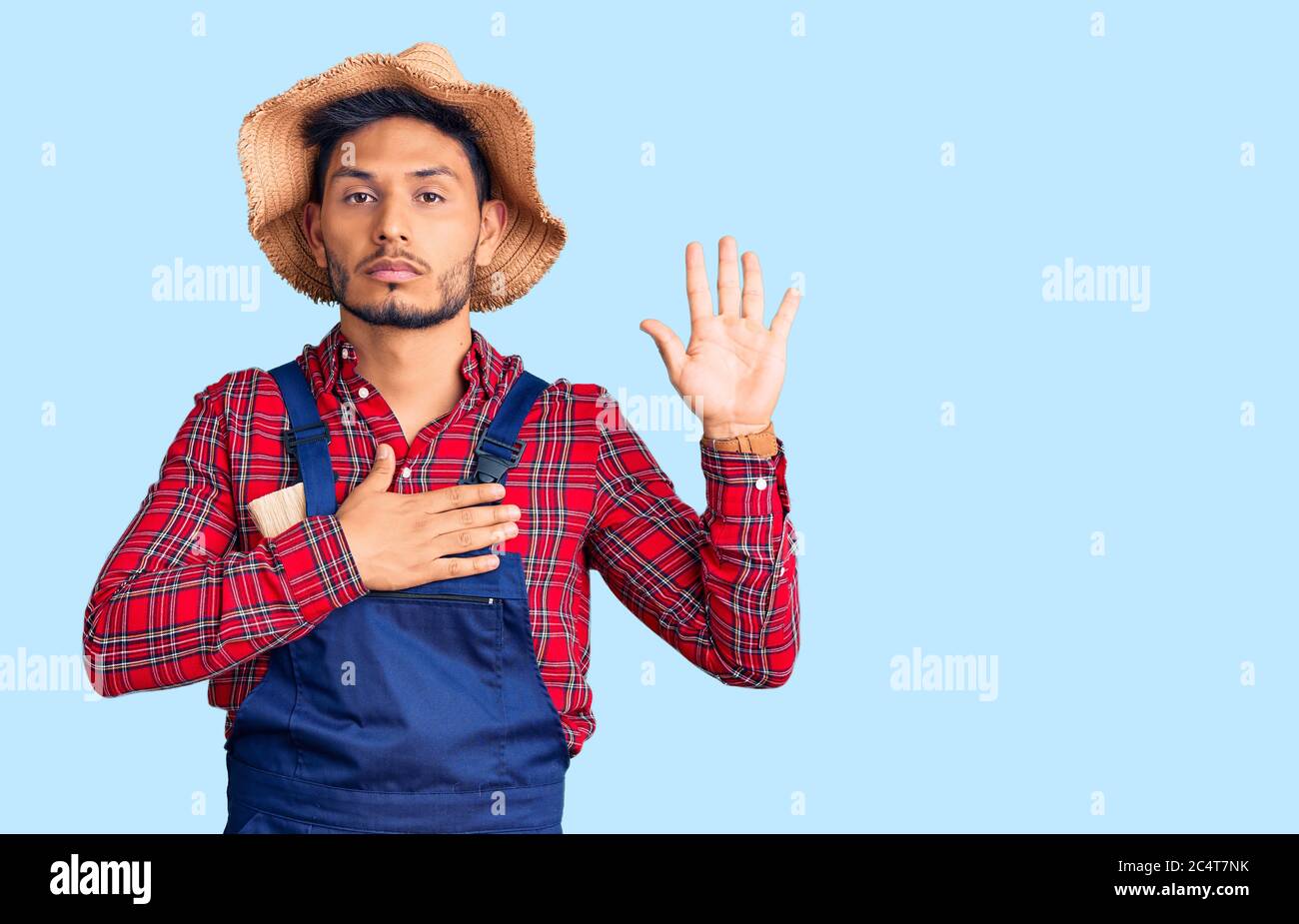 Handsome latin american young man weaing handyman uniform swearing with ...