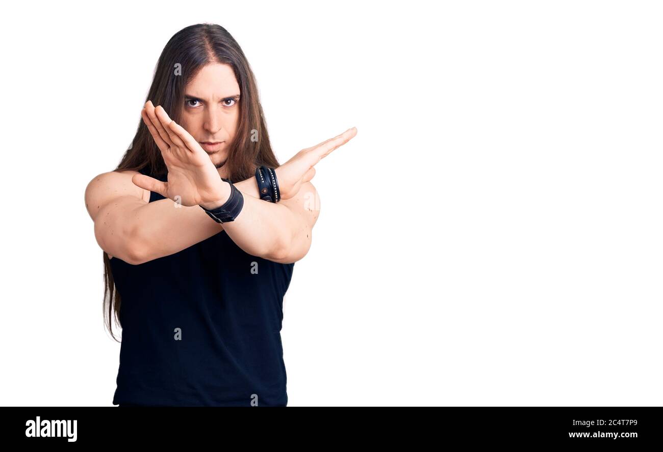 Young adult man with long hair wearing goth style with black clothes ...