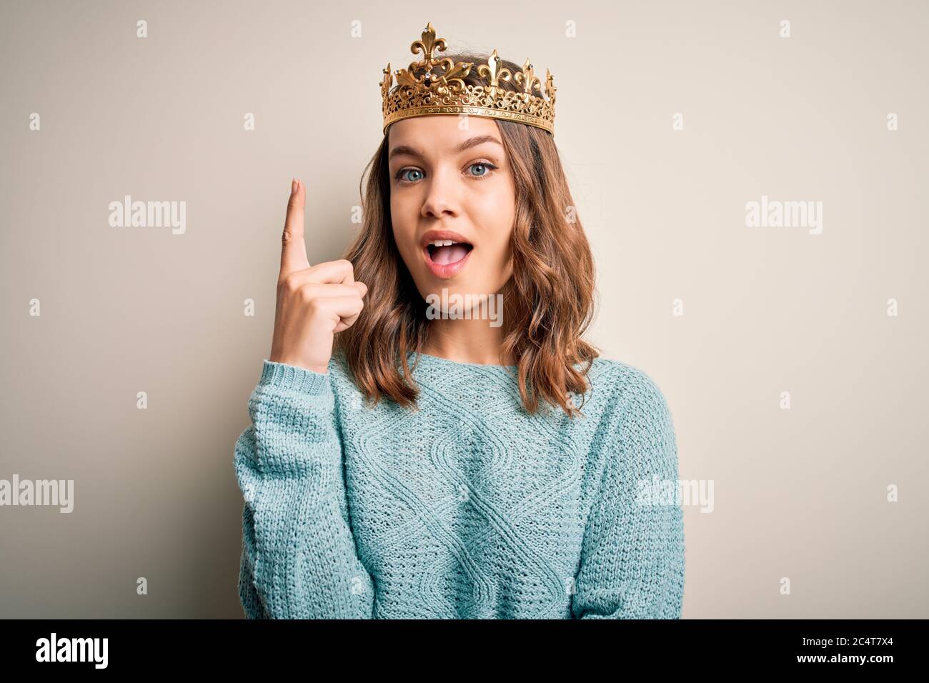 Young blonde girl wearing queen golden crown over isolated background ...