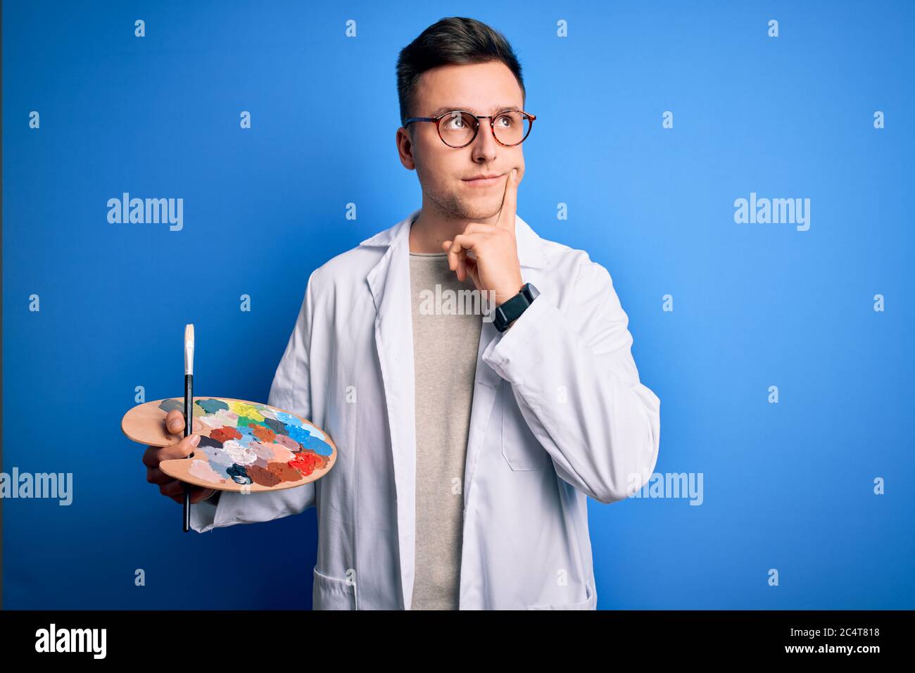 Young handsome caucasian artist man holding paintbrush and painter ...