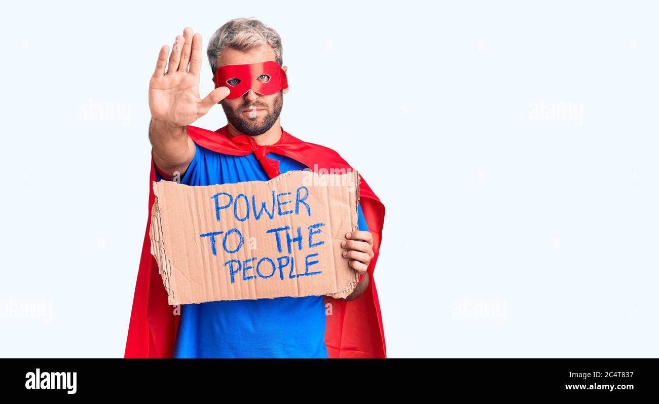 Young blond man wearing super hero custome holding power to the people ...