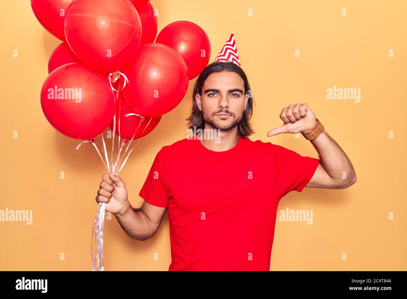 Young handsome man holding balloons with angry face, negative sign ...