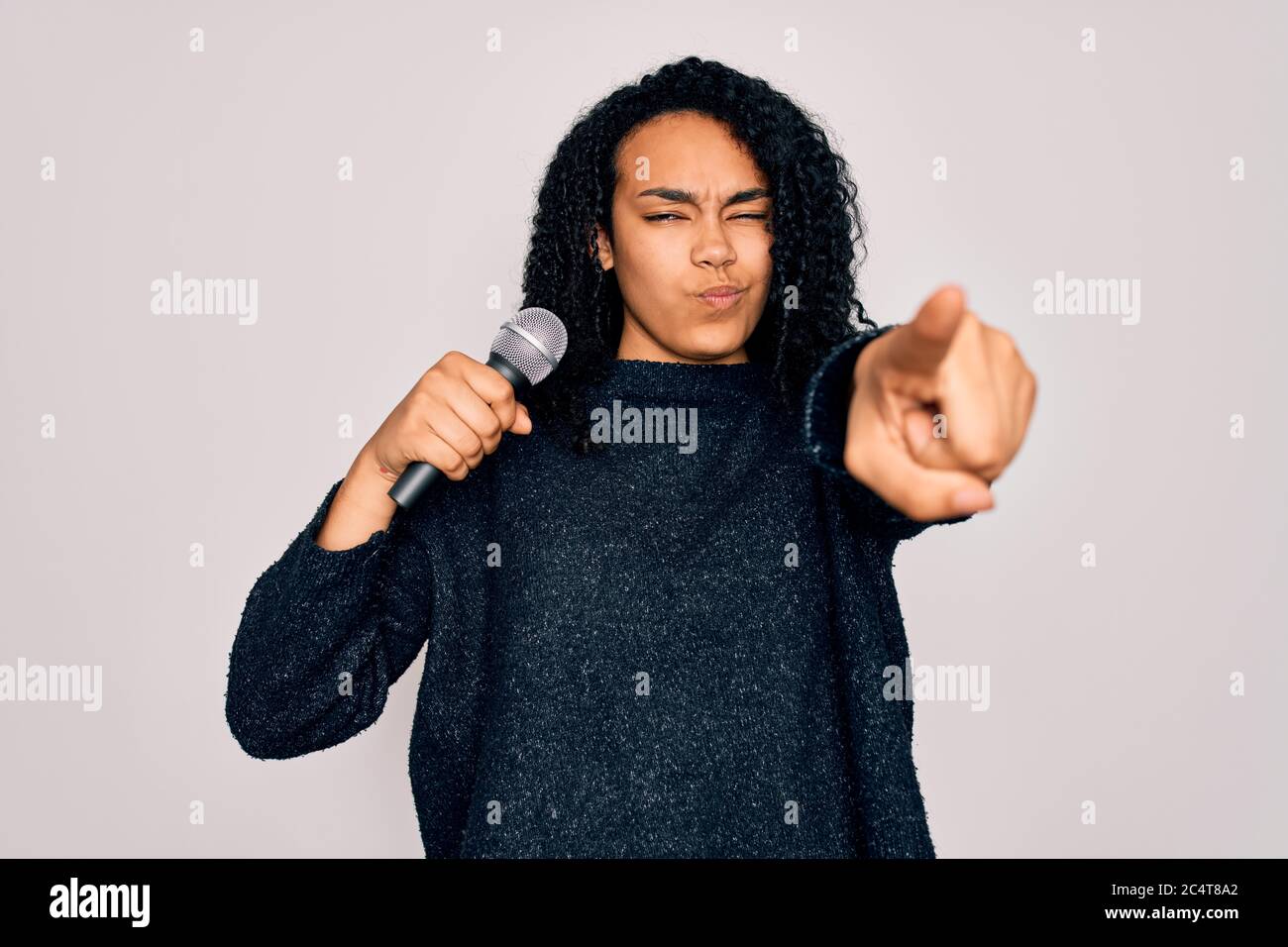 Young african american curly singer woman singing using microphone over ...