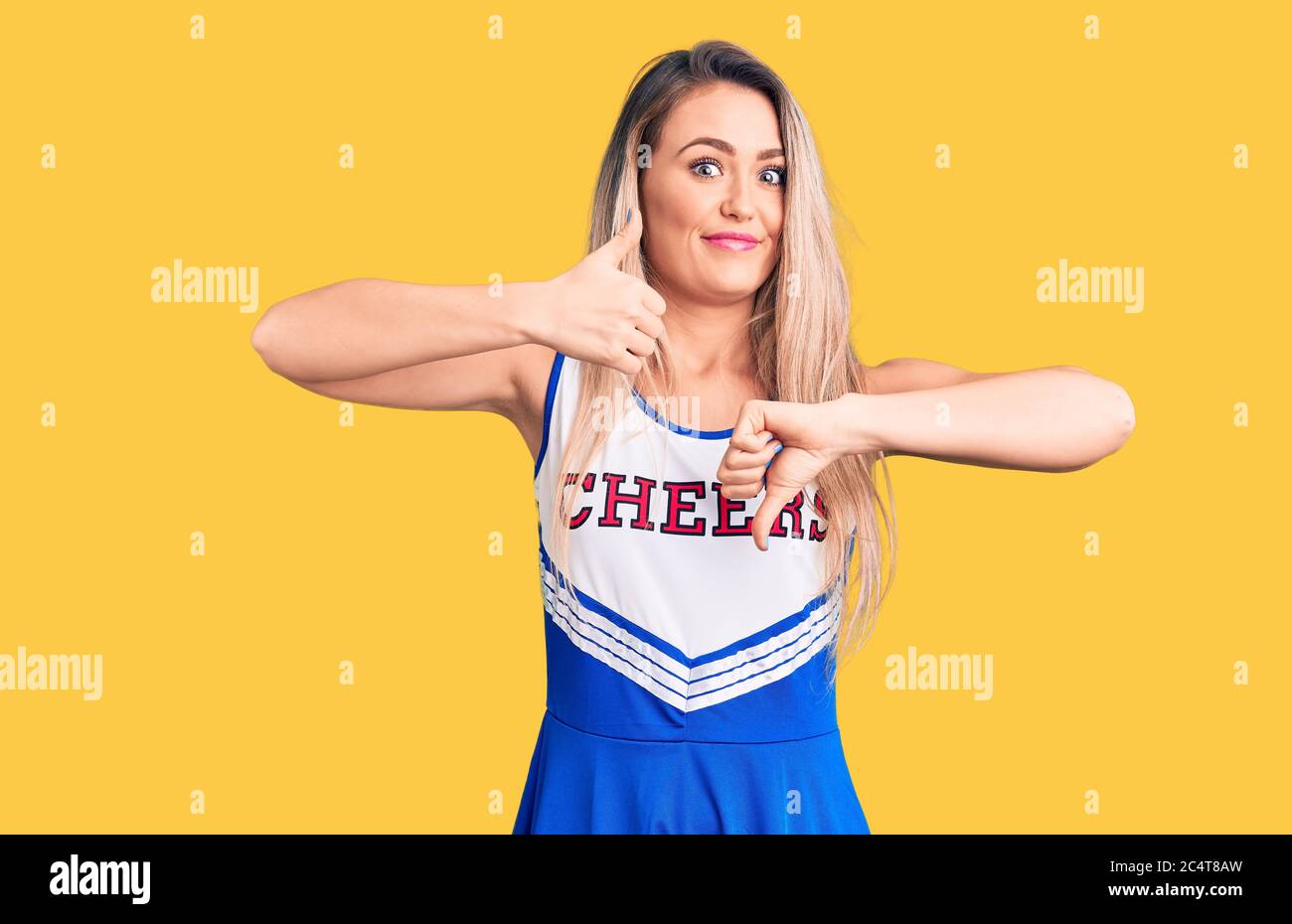 Young beautiful blonde woman wearing cheerleader uniform doing thumbs ...