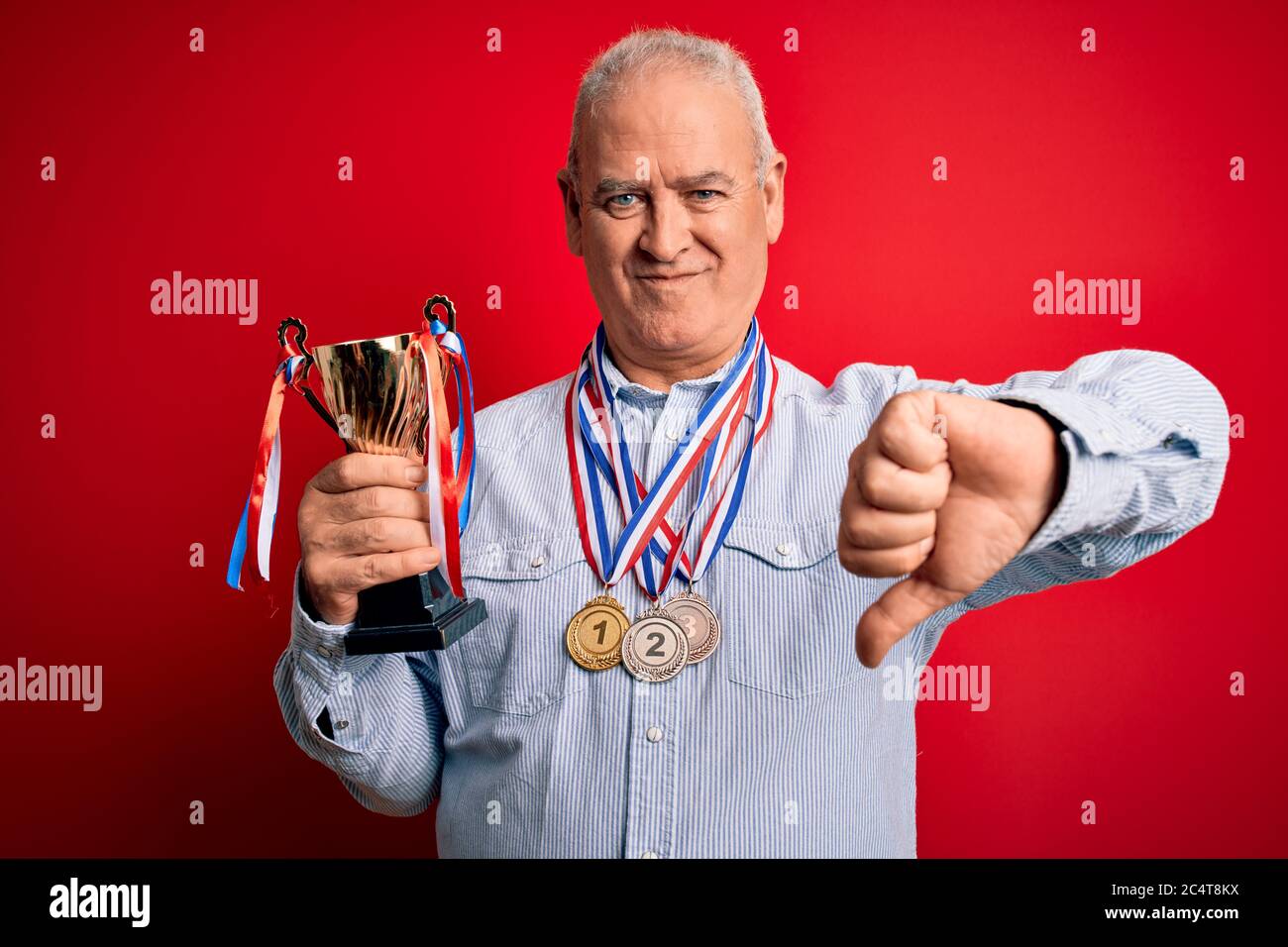Middle age hoary successful man wearing medals holding trophy over ...