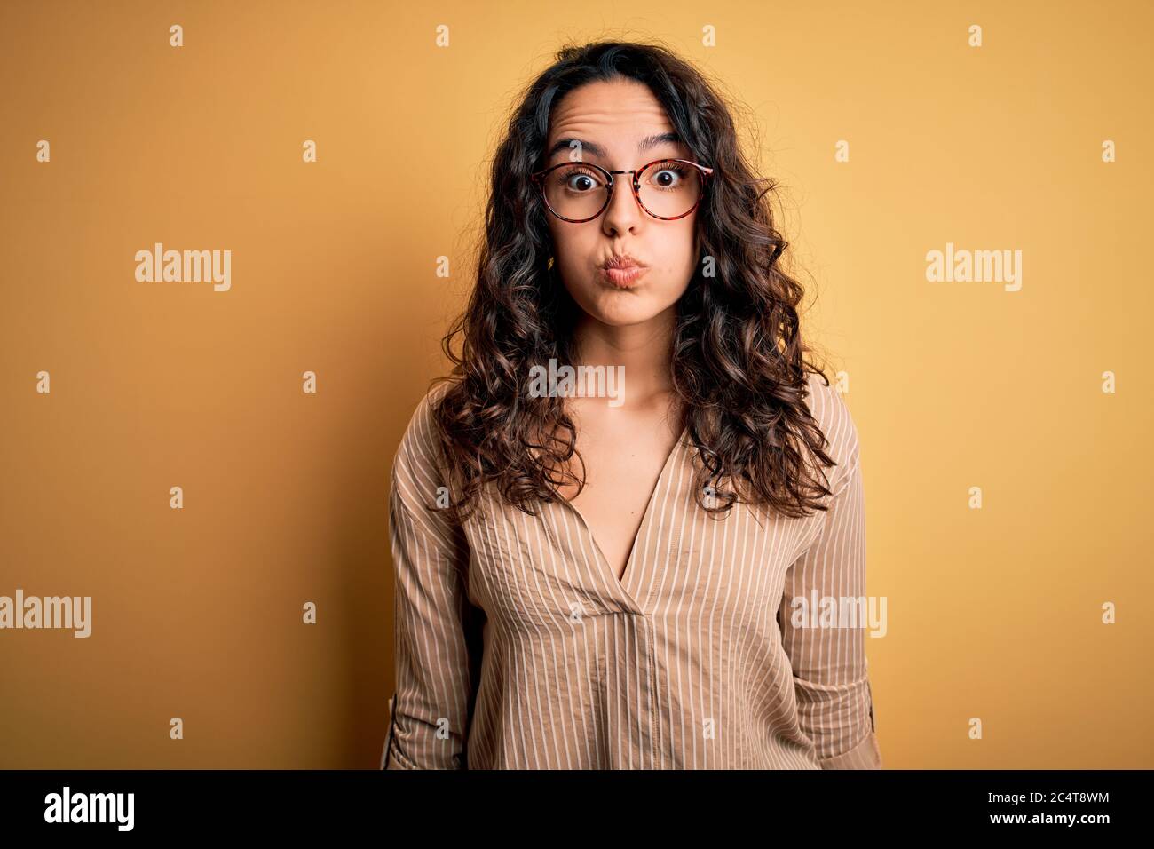 Beautiful woman with curly hair wearing striped shirt and glasses over ...