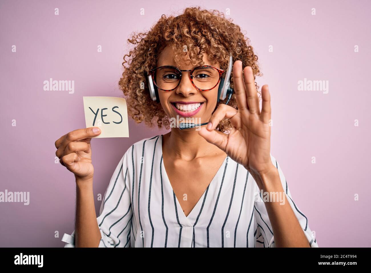 African american call center agent woman using headset holding reminder ...