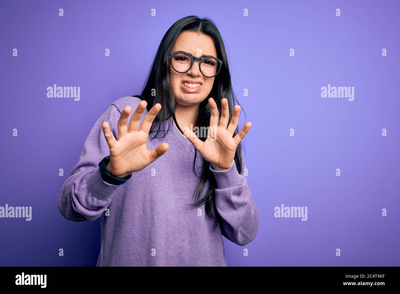 Young brunette woman wearing glasses over purple isolated background ...