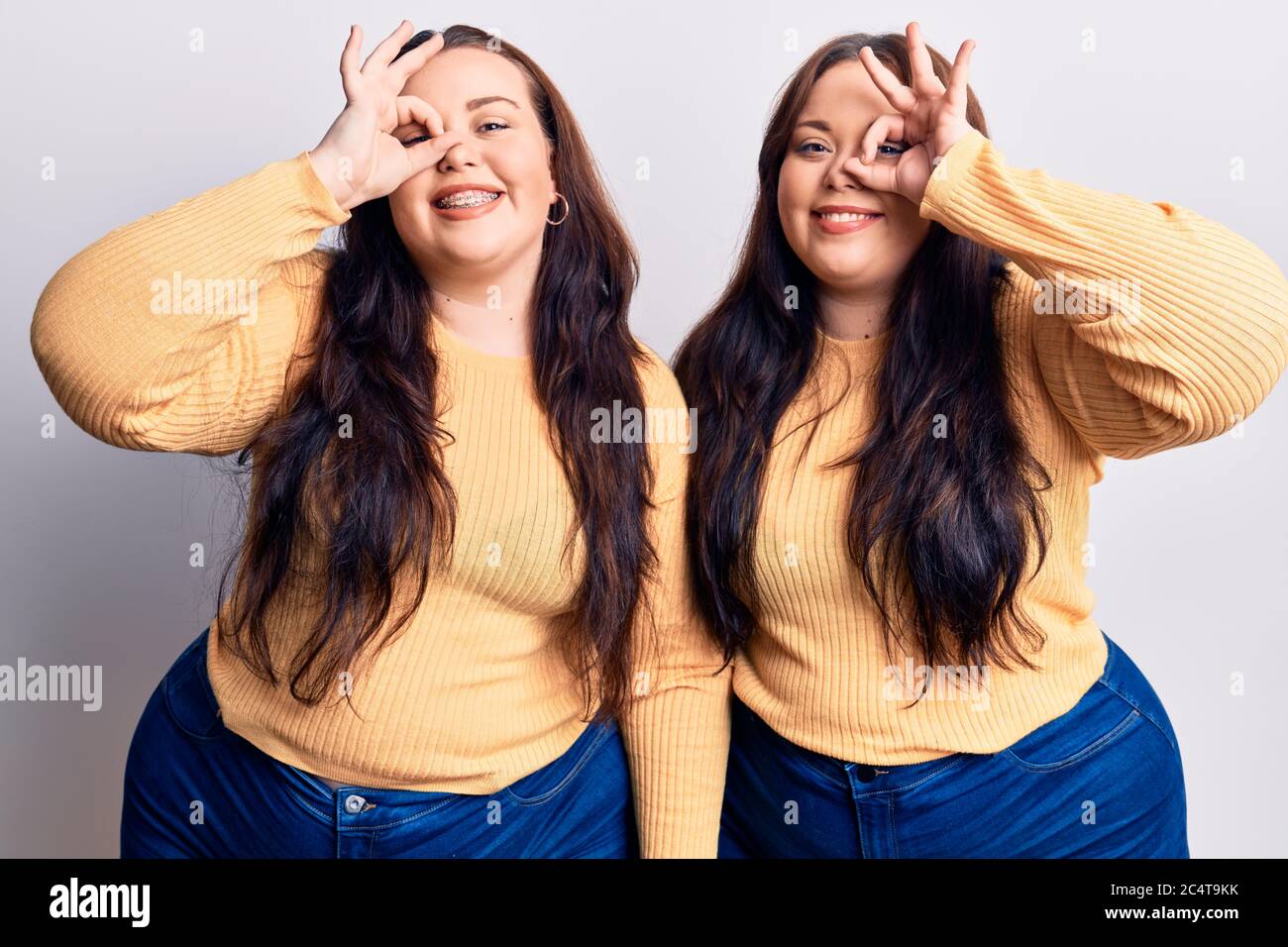 Young plus size twins wearing casual clothes doing ok gesture with hand ...