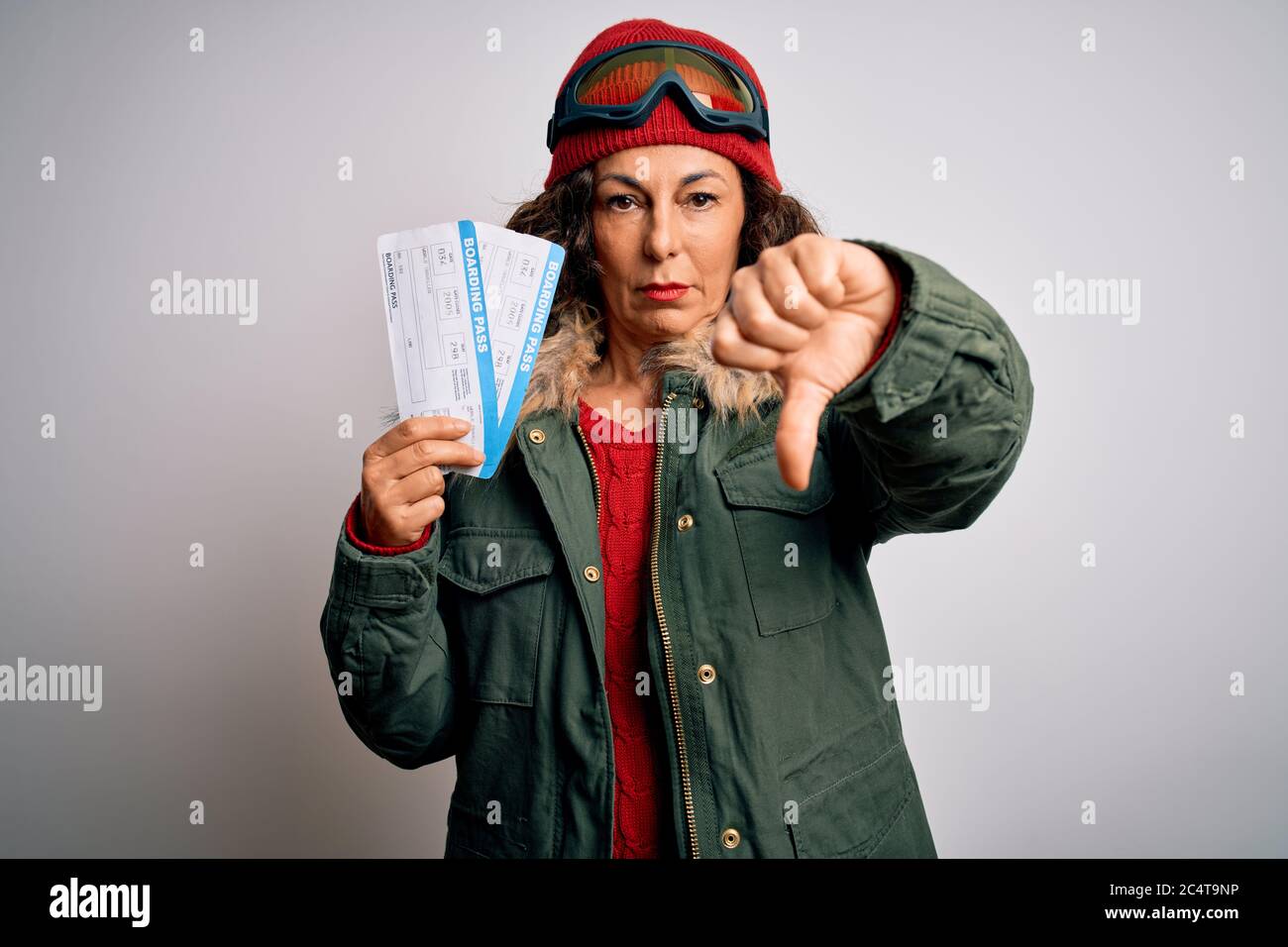 Middle age tourist woman wearing skier goggles holding airline boarding ...