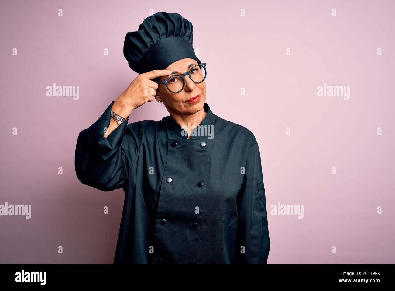 Middle age brunette chef woman wearing cooker uniform and hat over ...
