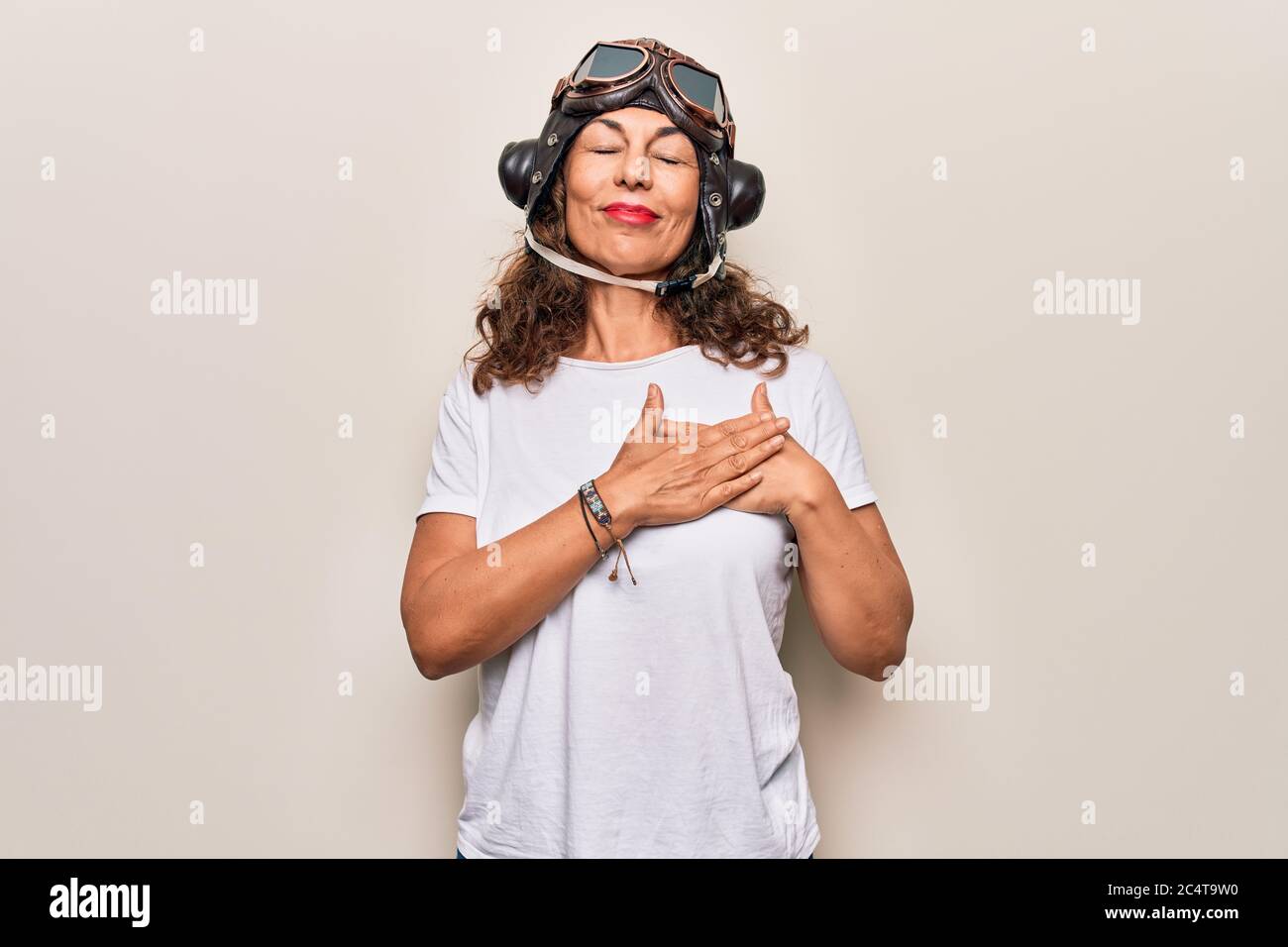 Middle age brunette woman wearing goggles and retro aviator leather hat ...