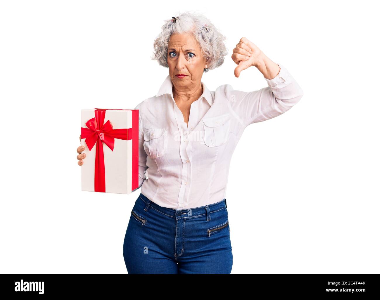 Senior grey-haired woman holding gift with angry face, negative sign ...