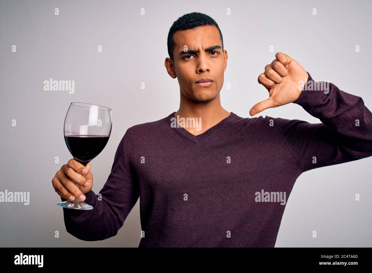 Handsome african american sommelier man tasting glass of red wine over ...