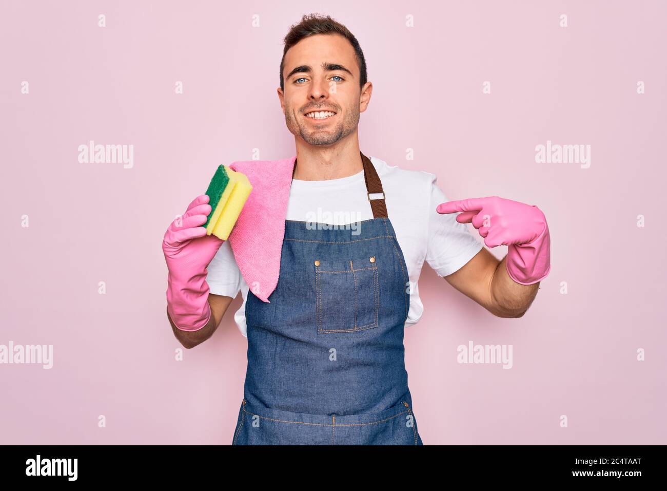 Young cleaner man with blue eyes cleaning wearing apron and gloves ...