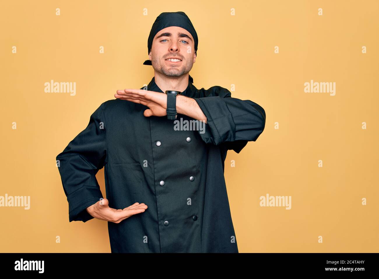 Young handsome cooker man with blue eyes wearing uniform and hat over ...