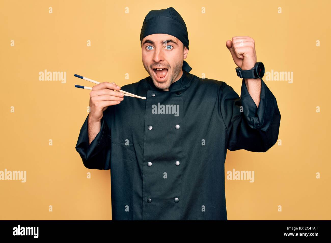Young handsome cooker man with blue eyes wearing uniform and hat using ...