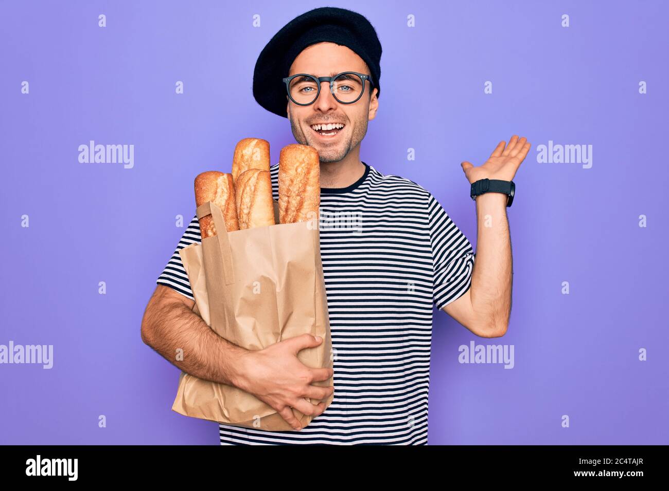 Young handsome baker man with blue eyes wearing french beret holding ...