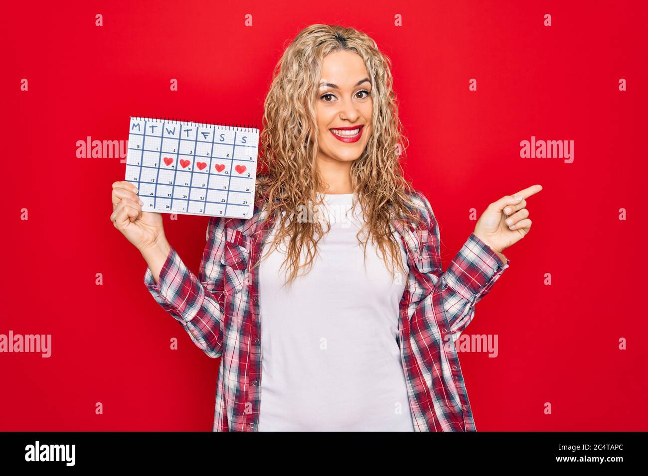 Young beautiful blonde woman holding period calendar controlling ...
