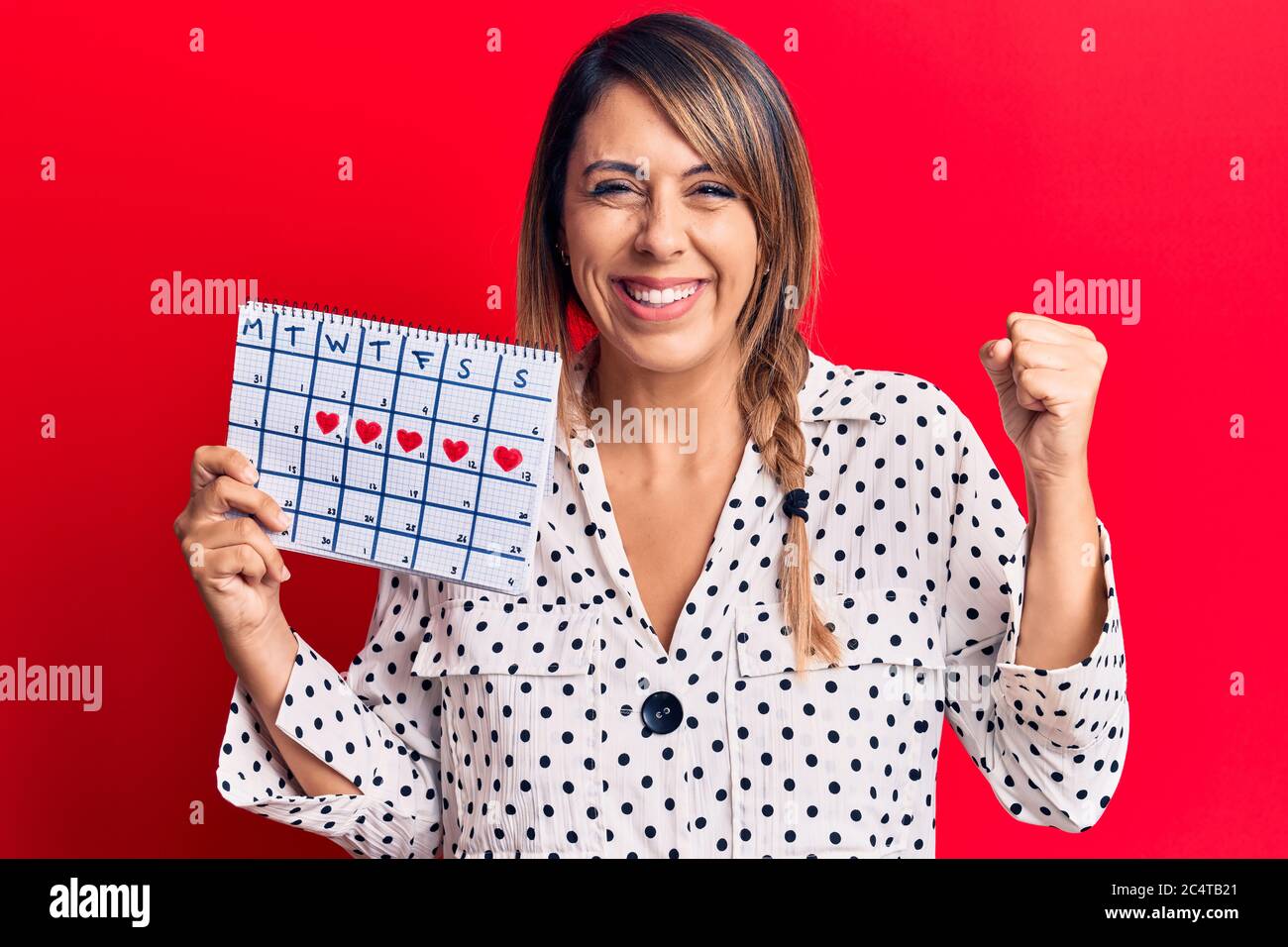Young beautiful woman holding period calendar screaming proud ...